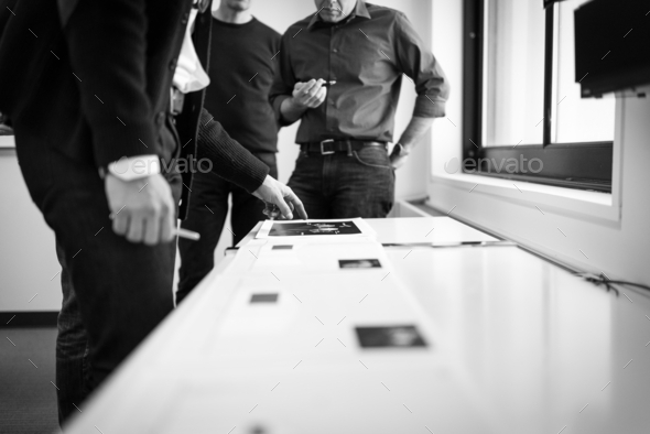 Design critique in the studio with designers gathered around the ...