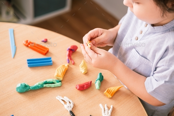 Little children's hands sculpt figurines from plasticine. An ...