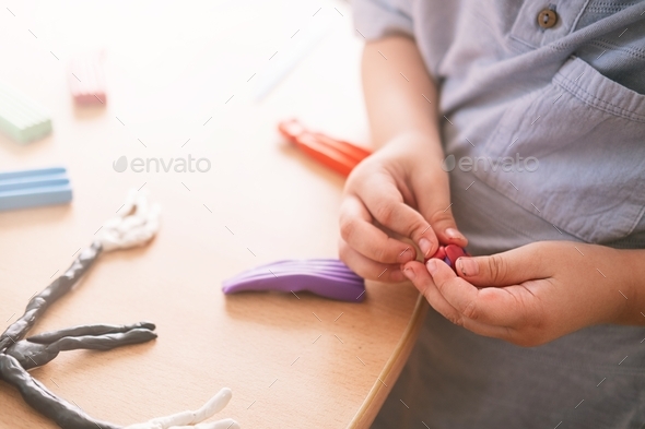 Little children's hands sculpt figurines from plasticine. An ...