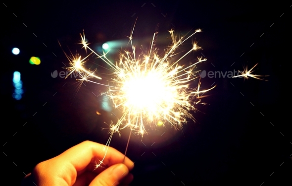 People holding firework in hand closeup in dark night outdoor blur ...