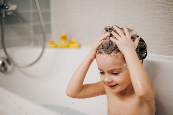 Little girl washing her head in the bathtub Stock Photo by anita_bonita