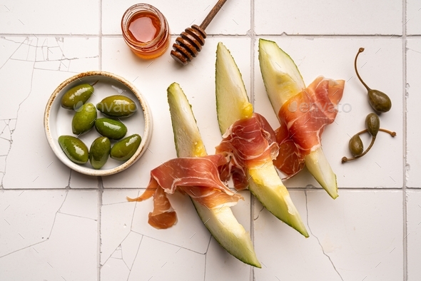 Jamon serrano, ham or prosciutto with melon and olives, a traditional ...