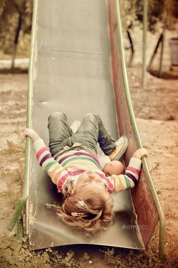 Little girl playing as she is sleeping on the slide Stock Photo by ...