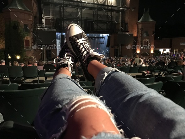 A woman with converse tennis shoes puts her feet up at an outdoor ...