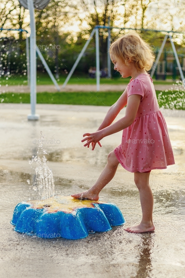 Girl playing at splash pad playground . Child at water park with ...