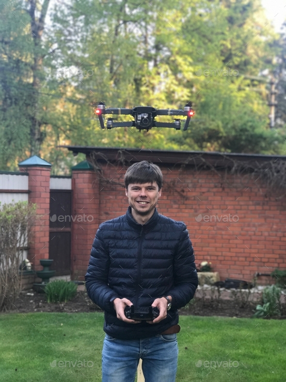 Young smiling male drone pilot using technology. Learning how to fly ...