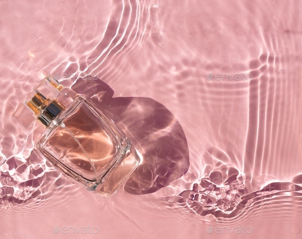 Transparent bottle perfume in pink water with shadows. Top view and ...