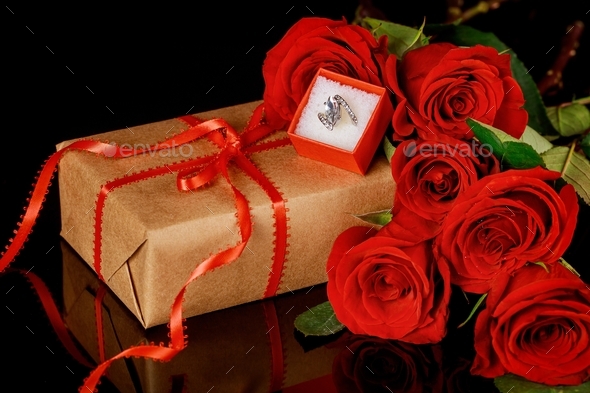 Ring in red box and beautiful red roses on black background. Valentines ...
