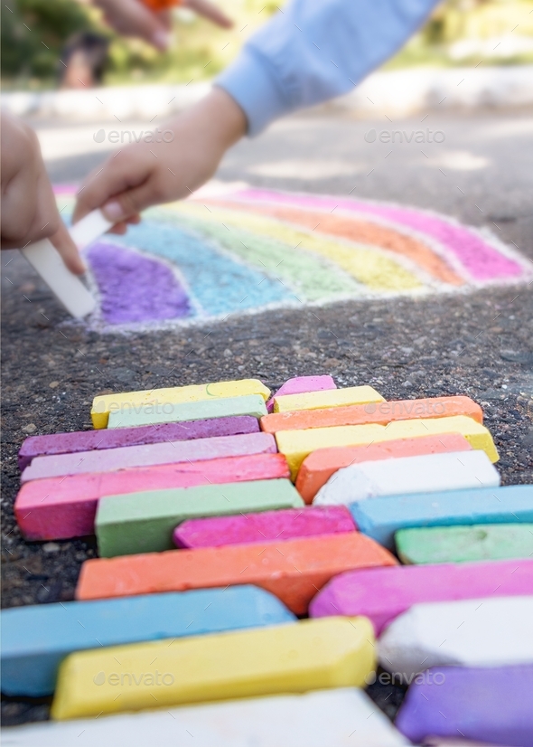children draw a rainbow on the pavement with colored crayons.childhood ...
