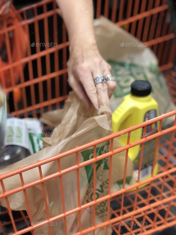 Woman bagging items just purchased and placing them in cart at ...