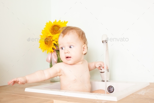 Baby taking bath in kitchen sink. Little boy bathing. Water fun for ...