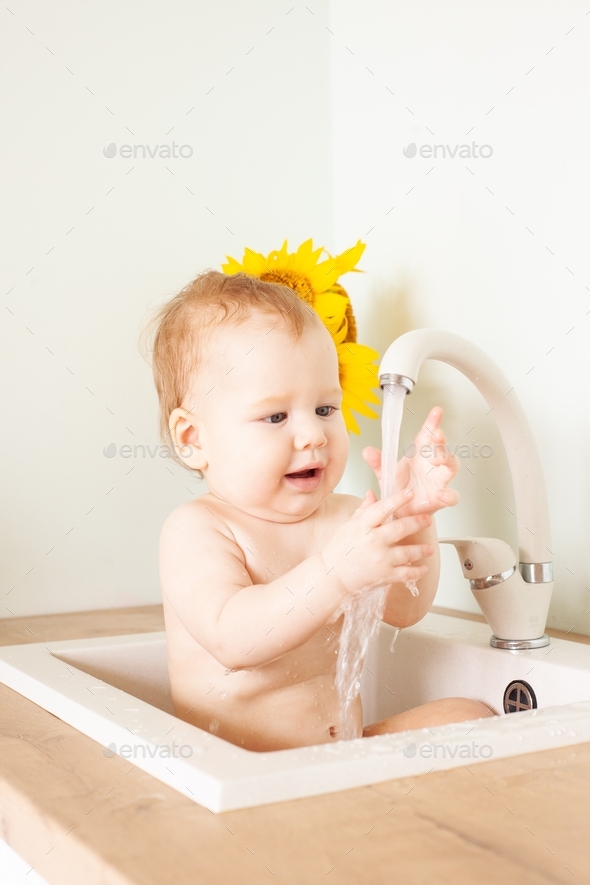 Baby taking bath in kitchen sink. Little boy bathing. Water fun for ...