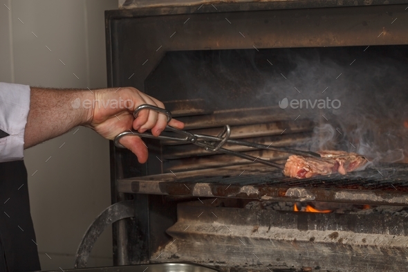 Chef makes beef steak on open fire in restaurant Stock Photo by Shandor_gor