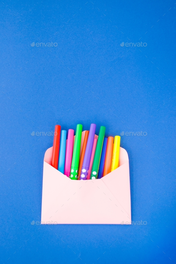 Paper pink envelope with markers inside on classic blue background with ...