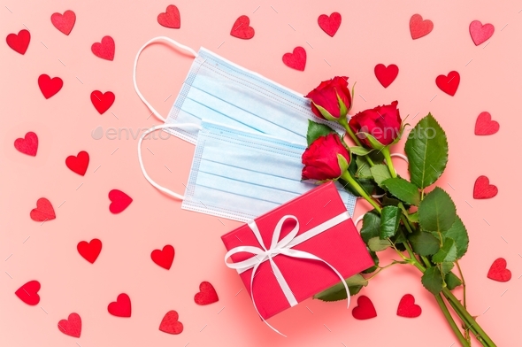Red roses, gift box and face masks on pink background with many wooden ...