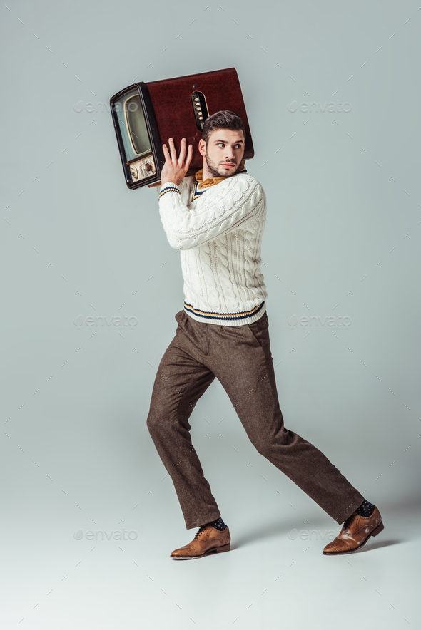 retro styled handsome man running away with vintage television on ...