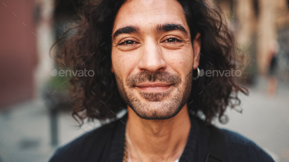 Young attractive italian guy with long curly hair and stubble looks ...