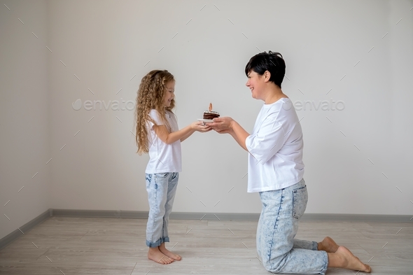 Mother giving a piece of cake to her daughter Stock Photo by ...