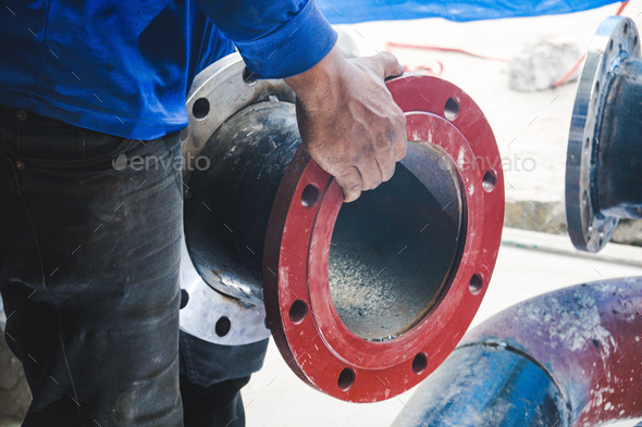 Workers are lifting parts of the pipe system to prepare for assembly ...