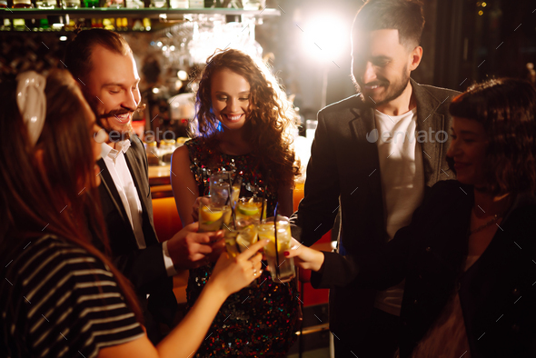 Cheering, drinking cocktails. Group of friends partying in a nightclub ...
