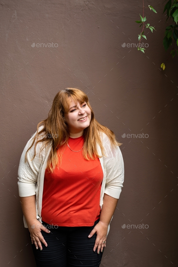 Body positive. Confident overweight woman posing on the brown solid ...