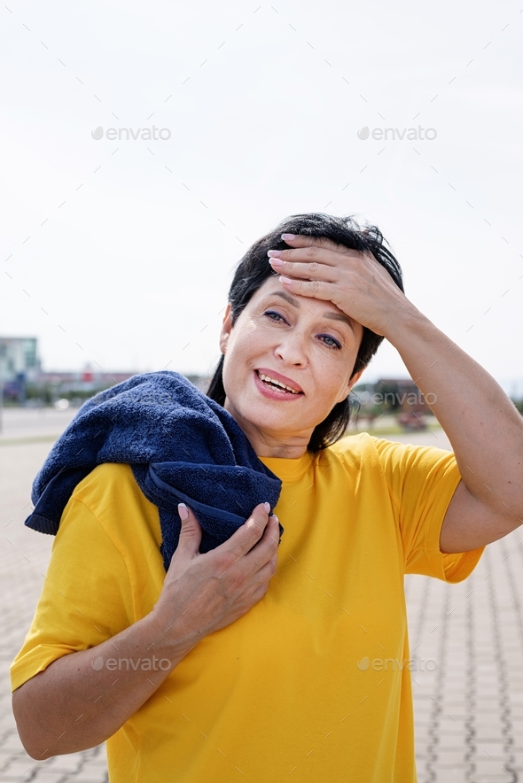 Smiling senior woman wiping out sweat after hard workout outdoors in ...