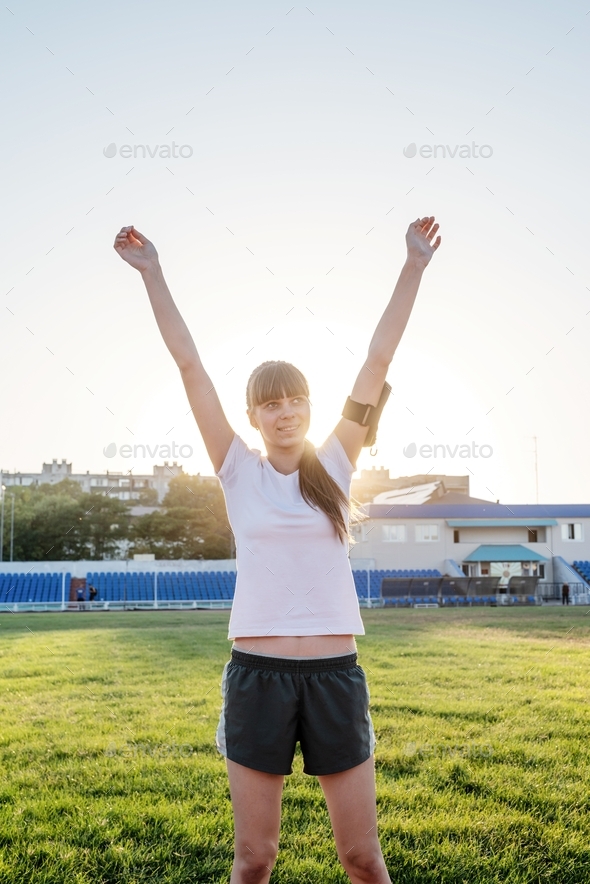 Young sports girl standing on the track and rising her hand Stock Photo ...