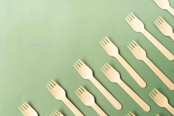 Disposable wooden forks top view on green background with copy space ...