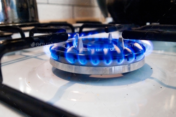 Macro closeup of modern luxury gas stove top with blue fire flame knobs ...