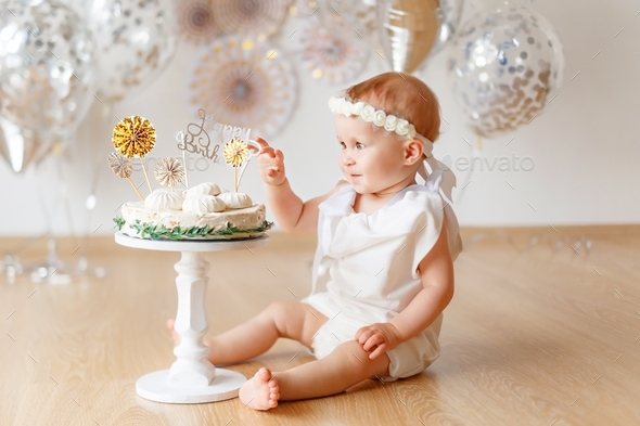Little baby girl touching her first birthday cake, smash the cake ...
