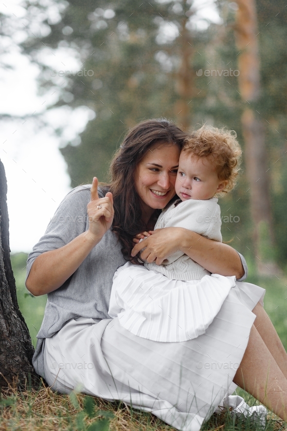 Young attractive mother hugging her little Carly daughter and talking ...