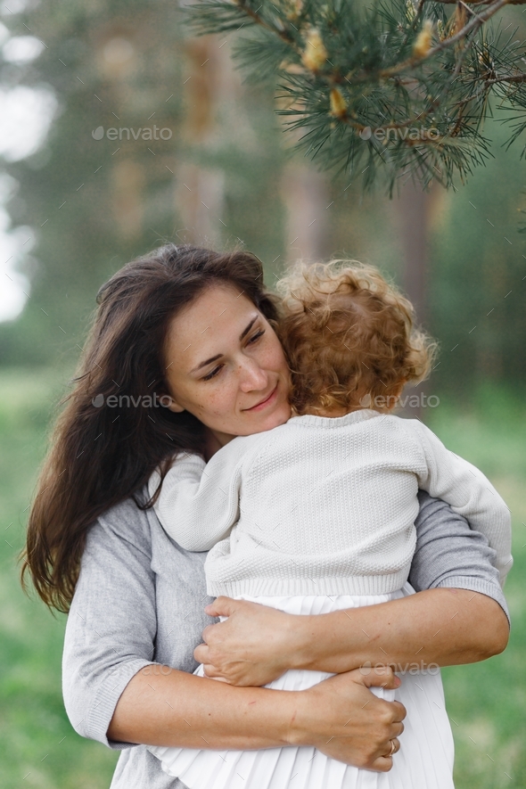Mother hugging her little daughter while walking in park outdoors in summer Stock Photo by ...