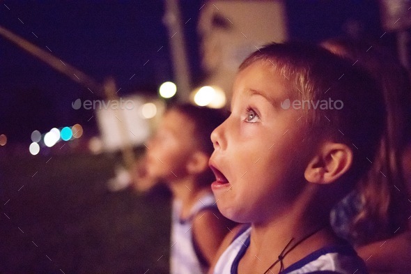 Boy watching fireworks with a very surprised face after they went ...