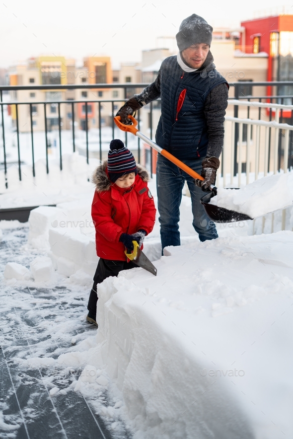 Dad and son together building an igloo out of snow bricks. Outdoor ...