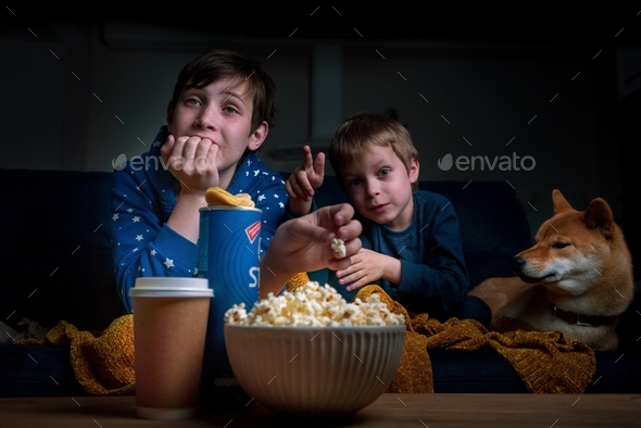 Movie night. Sleepy kids watching movies and eating popcorn and Lays at ...