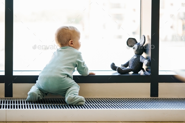 View from behind of the cutest baby looking through window on outdoor ...