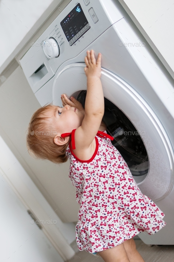 Child with washing machine. Little girl is helping with family chores ...
