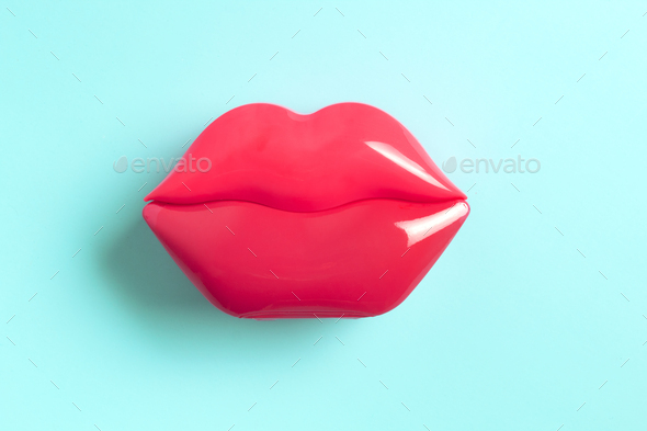Artificial red lips shape on blue background. Flat lay. Beauty, care ...