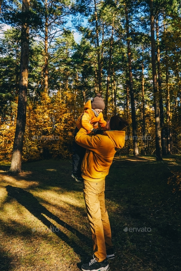 Father and son having fun in autumn forest. Profile view, vertical ...
