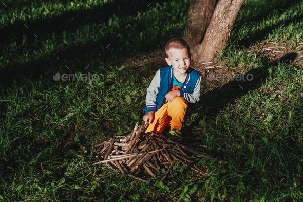 boy collect sticks in the park to play in a hut or a bonfire Stock ...