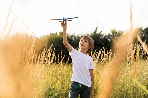 A little boy with a toy plane in his hand against the blue sky, dream ...