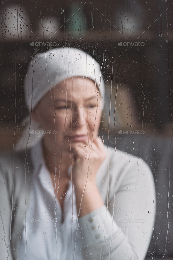 sick mature woman in kerchief crying behind window with raindrops Stock ...