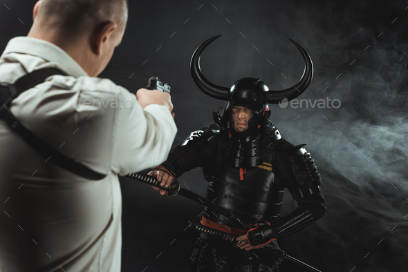 man aiming on armored samurai with gun Stock Photo by LightFieldStudios