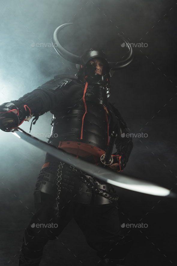 bottom view of samurai in traditional armor with sword on dark ...