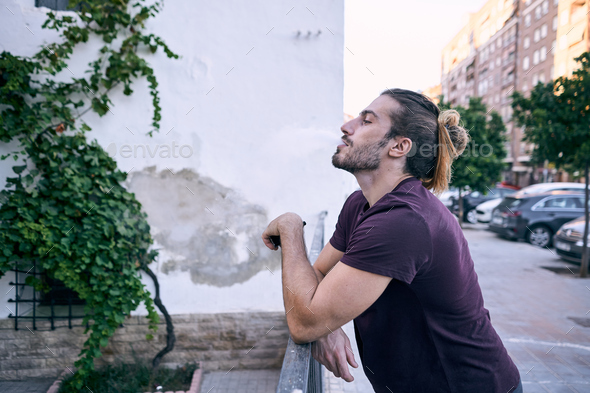 caucasian guy standing in a black t-shirt exhaling vaping smoke leaning ...
