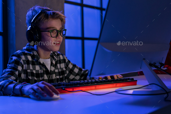 Young gamer boy with headphones playing computer video game. Stock ...