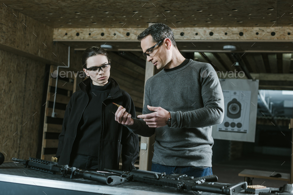 instructor describing bullet to female client in shooting range Stock ...