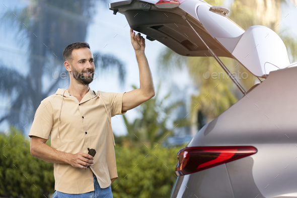 Latin man driver opening car trunk planning road trip. Transportation ...