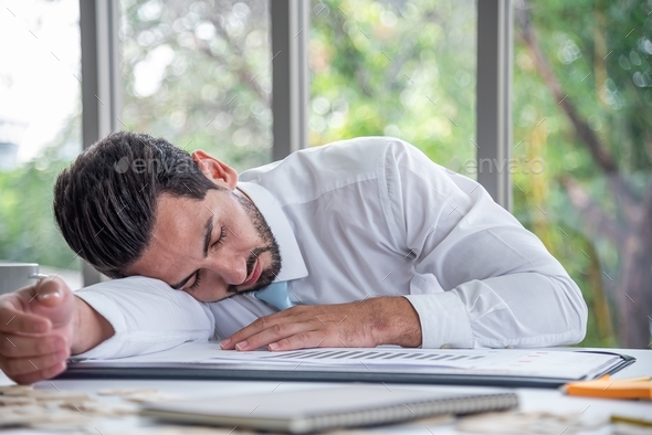 Tired businessman lying tired at work Stock Photo by mrzphotoproducer