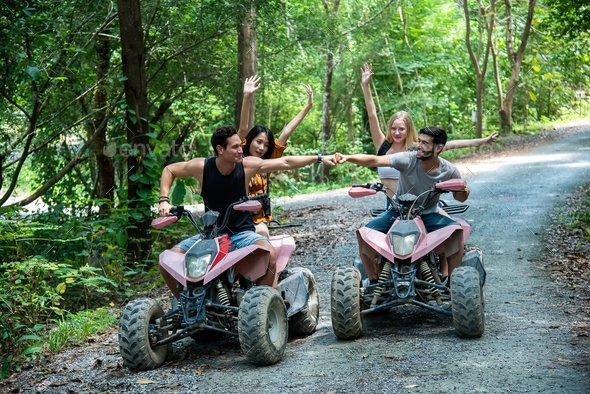 young couple or friend happily touches their hands while riding an ATV ...